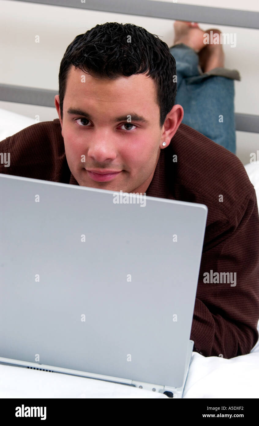 Hispanic man working on laptop computer while lying on bed Stock Photo ...