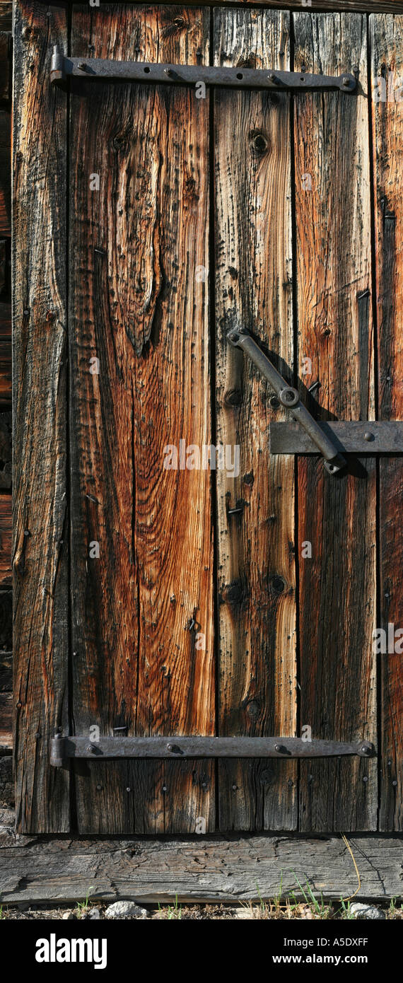 Weathered wooden barn door with rusted iron hinges in rural western ...