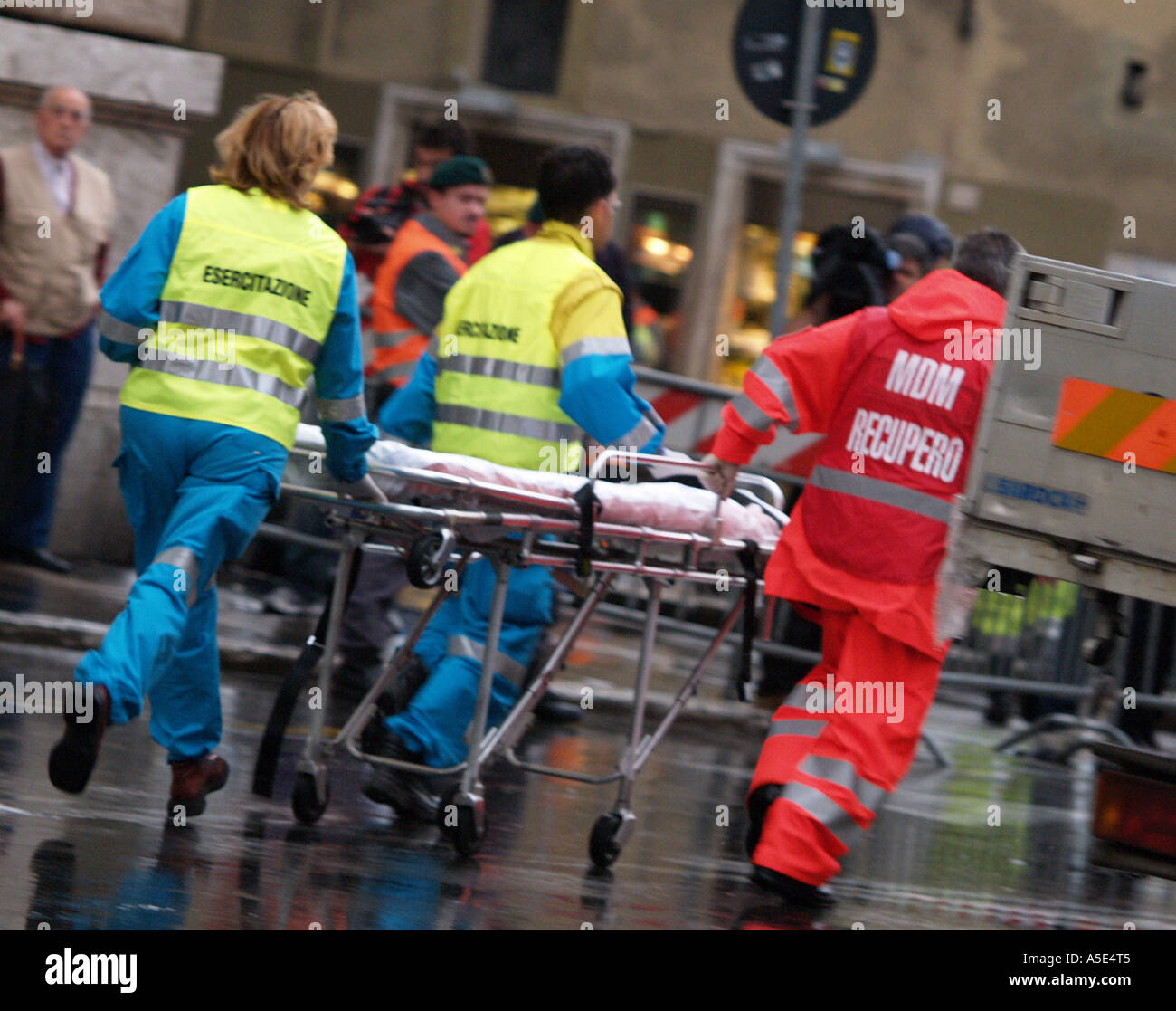 paramedics and stretcher trolley running down wet street in Rome during ...