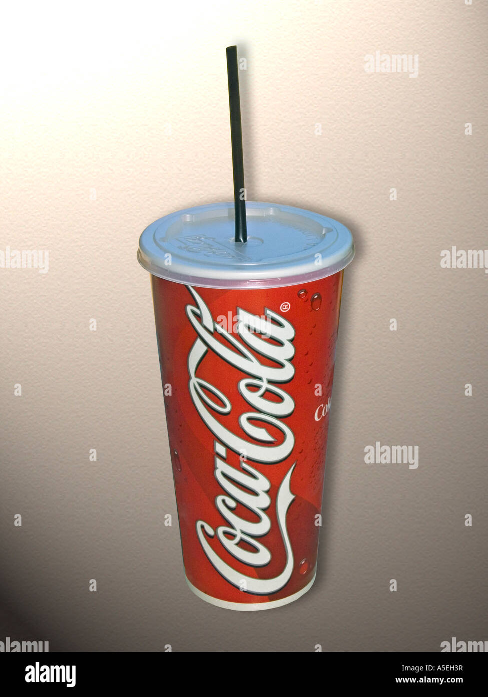 Red Coca cola milkshake container and straw against a ligth coloured ...