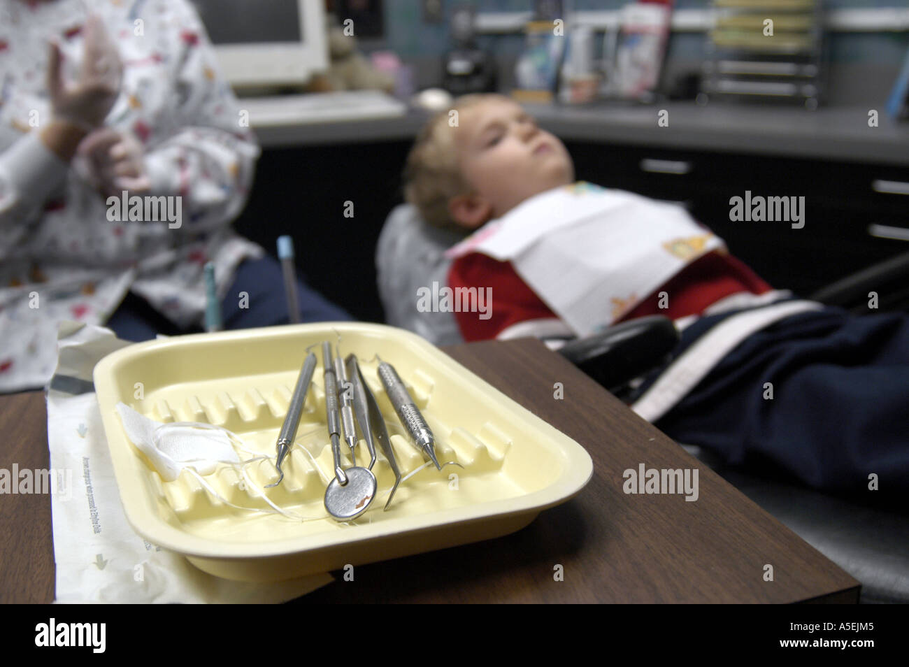Dental Tools on counter as 3 Year-old Boy lays in chair nervously ...