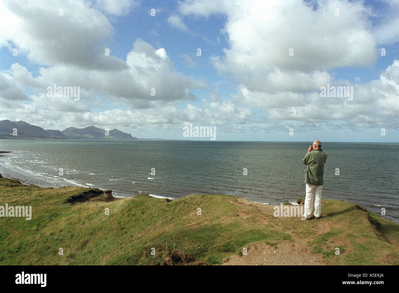 man taking photo by dinas dinlle beach in wales Stock Photo - Alamy