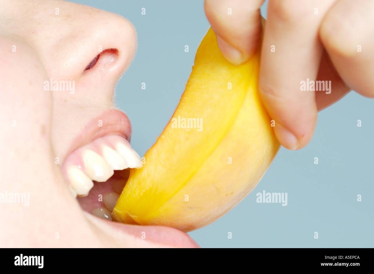 peachy bites woman biting into a piece of peach Stock Photo - Alamy