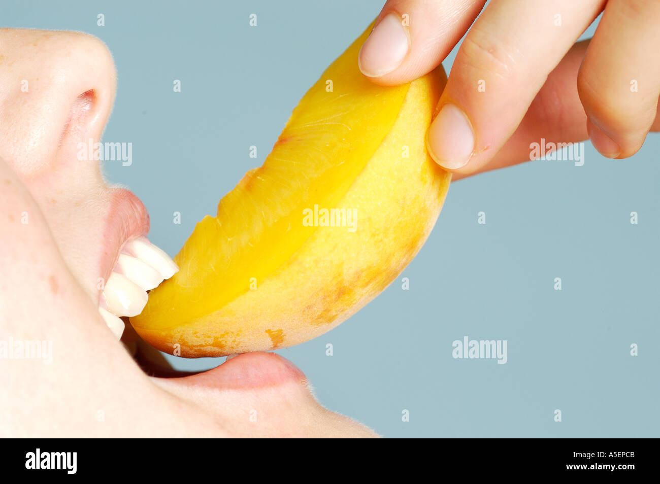 peachy bites woman biting into a piece of peach Stock Photo - Alamy