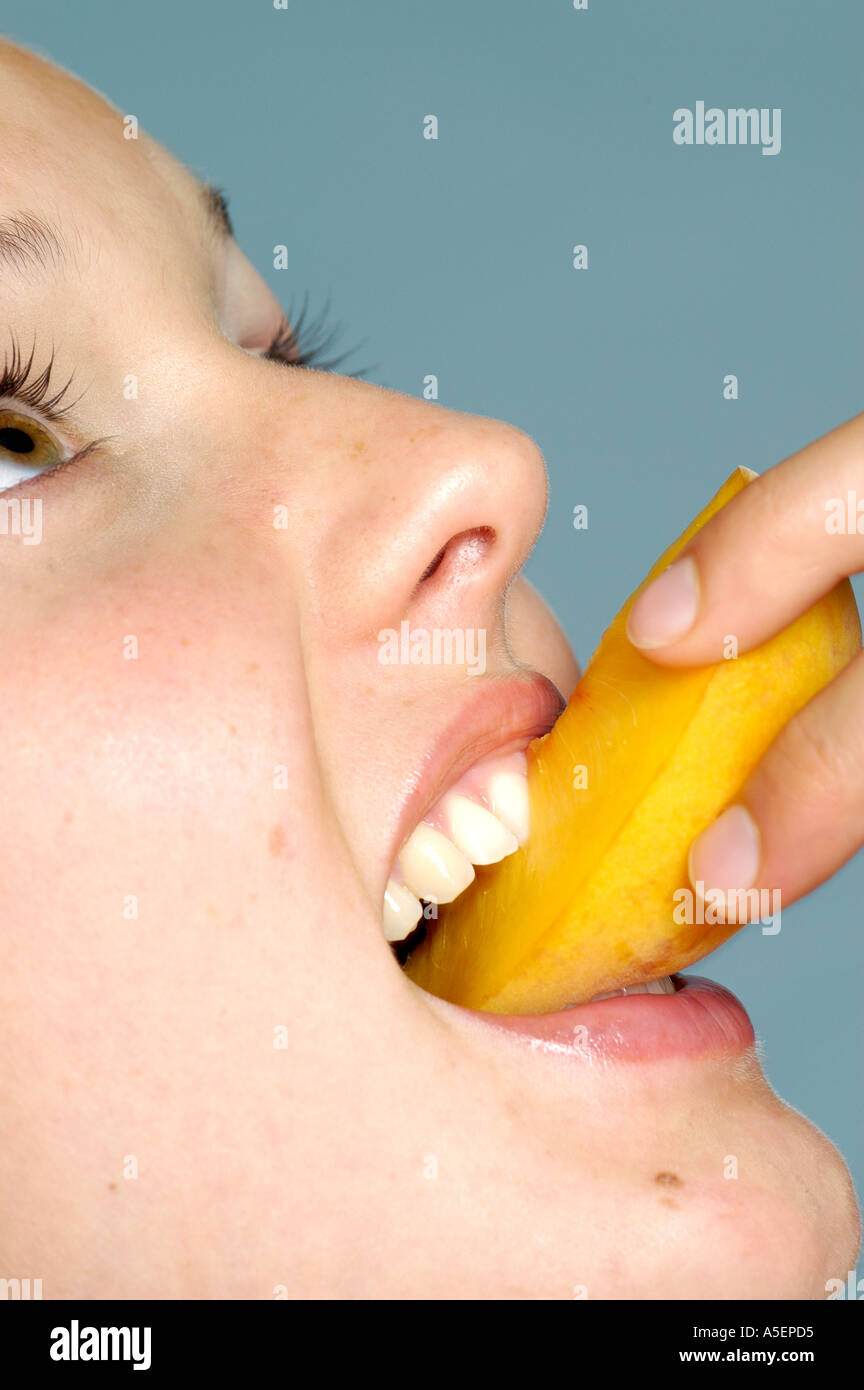 peachy bites woman biting into a piece of peach Stock Photo - Alamy