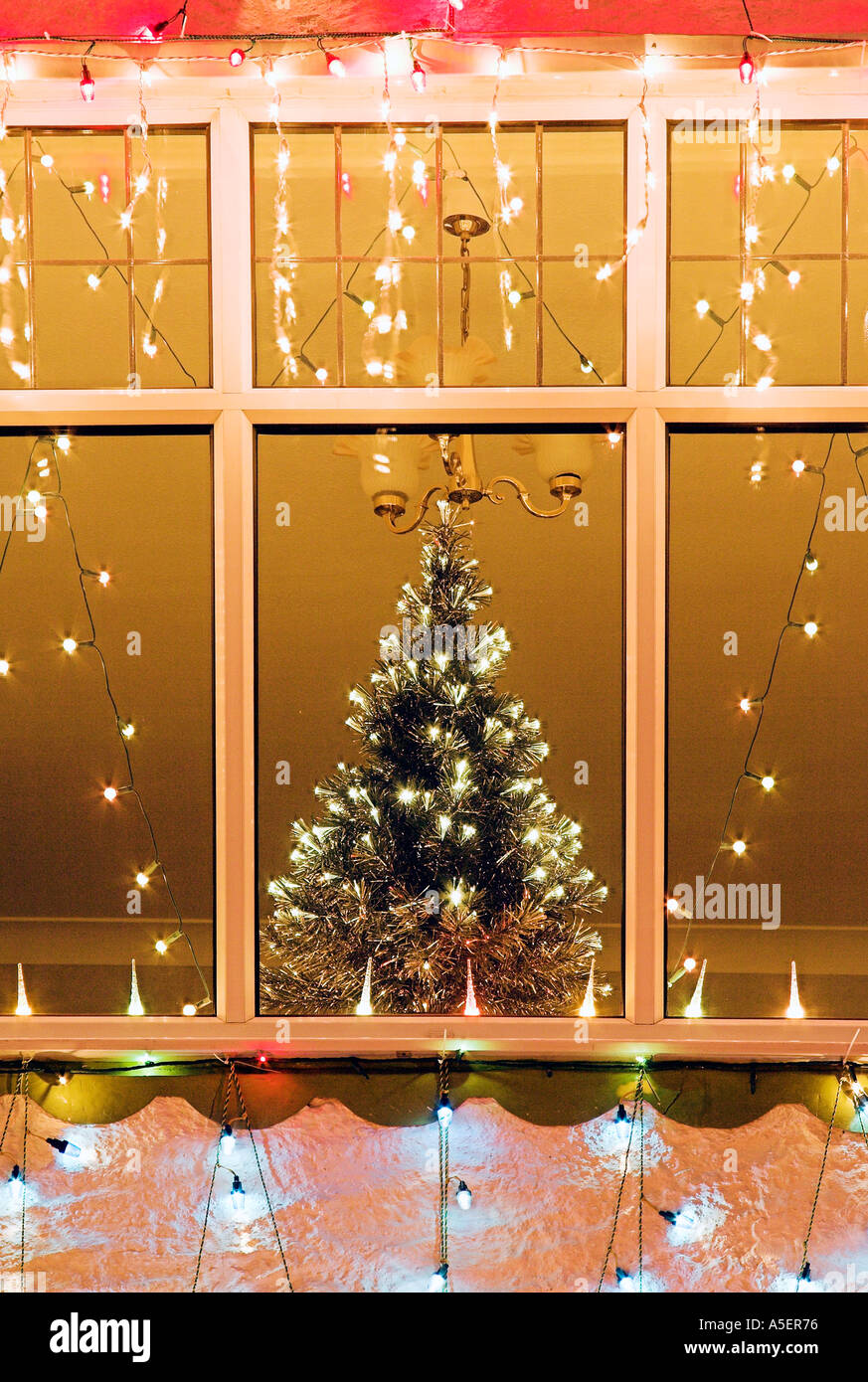 Christmas tree and fairy lights arranged around window Stock Photo - Alamy