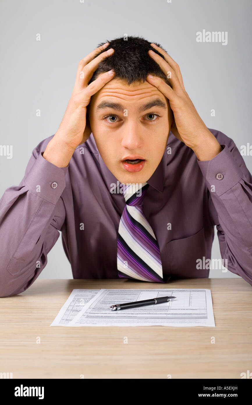 Shocked man at the desk There s some papers on the desk and a pen paper ...