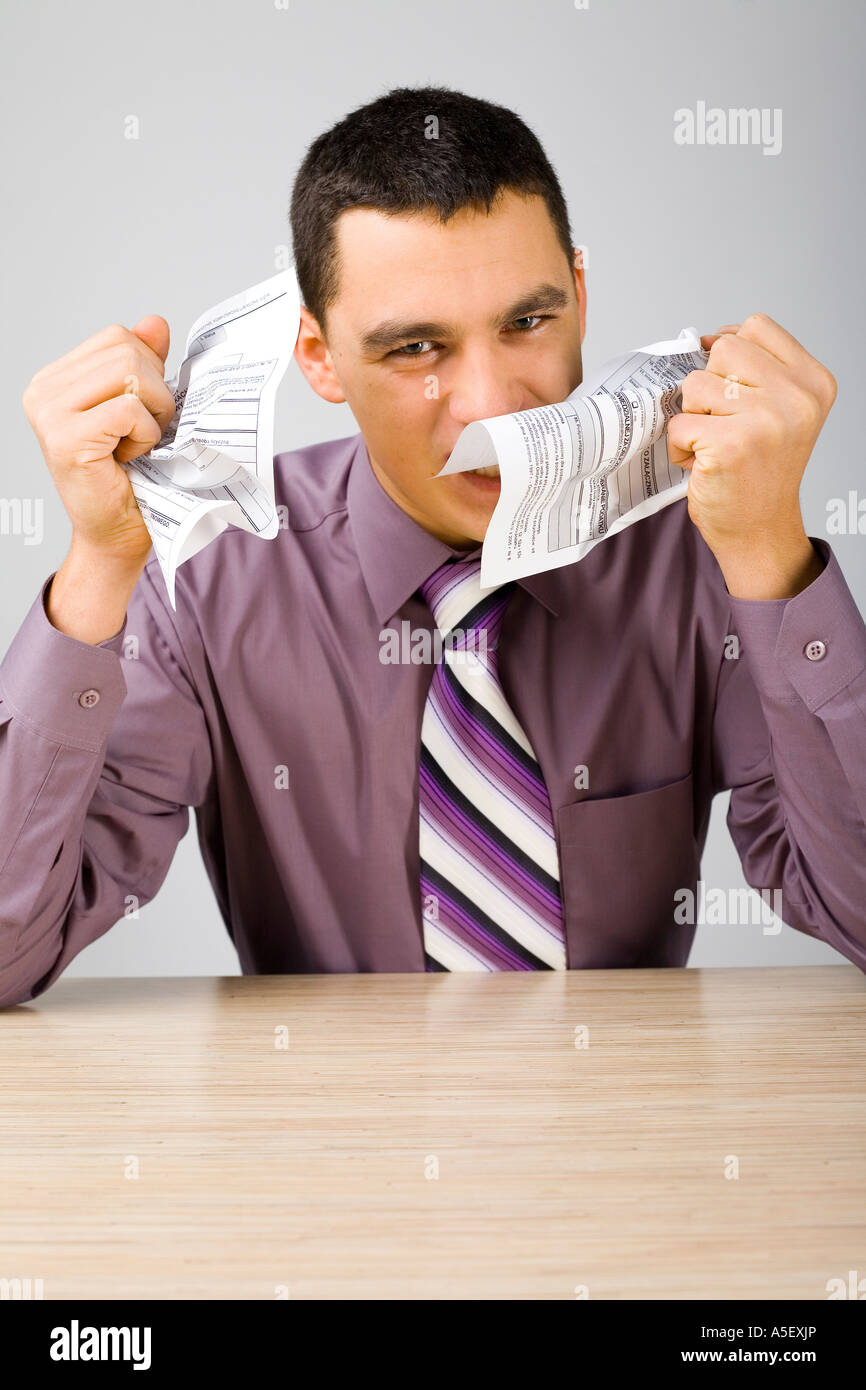 Angry man at the desk crumpling two sheets of paper paper s form is ...