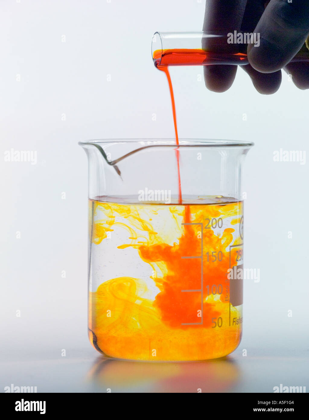 Orange dye from test tube being poured into glass beaker Stock Photo ...