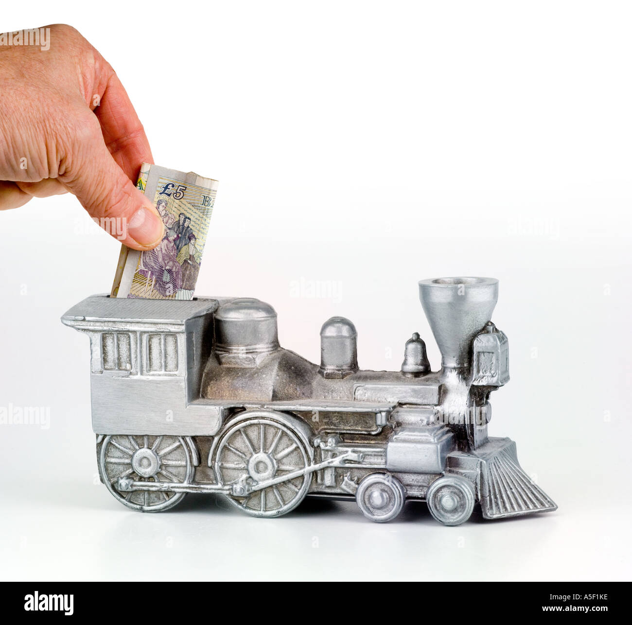 Pewter train moneybox with hand putting in 5 five pound note Stock ...