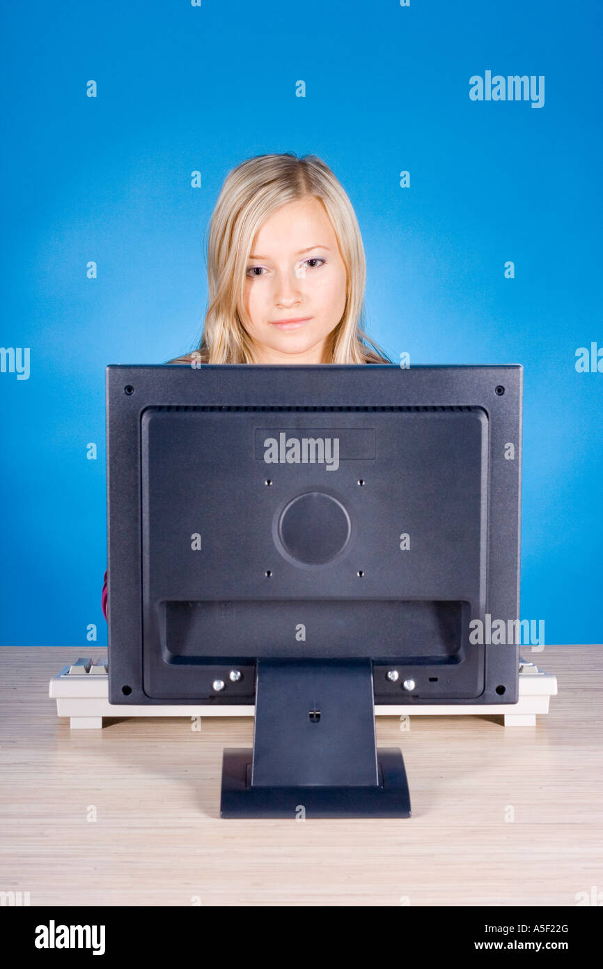young blonde woman at the computer blue background Stock Photo - Alamy