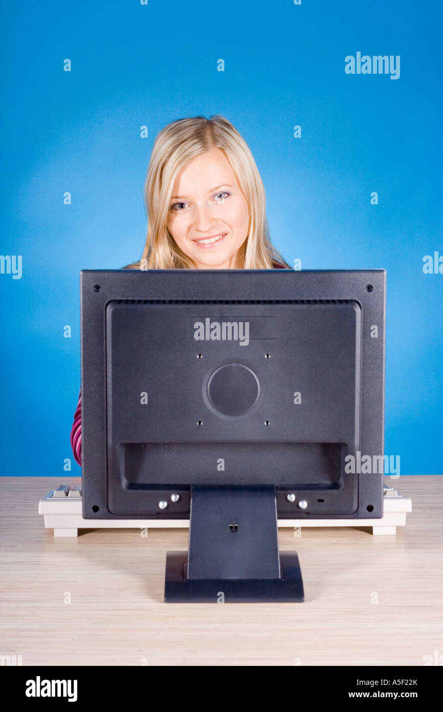 young blonde woman at the computer blue background Stock Photo - Alamy