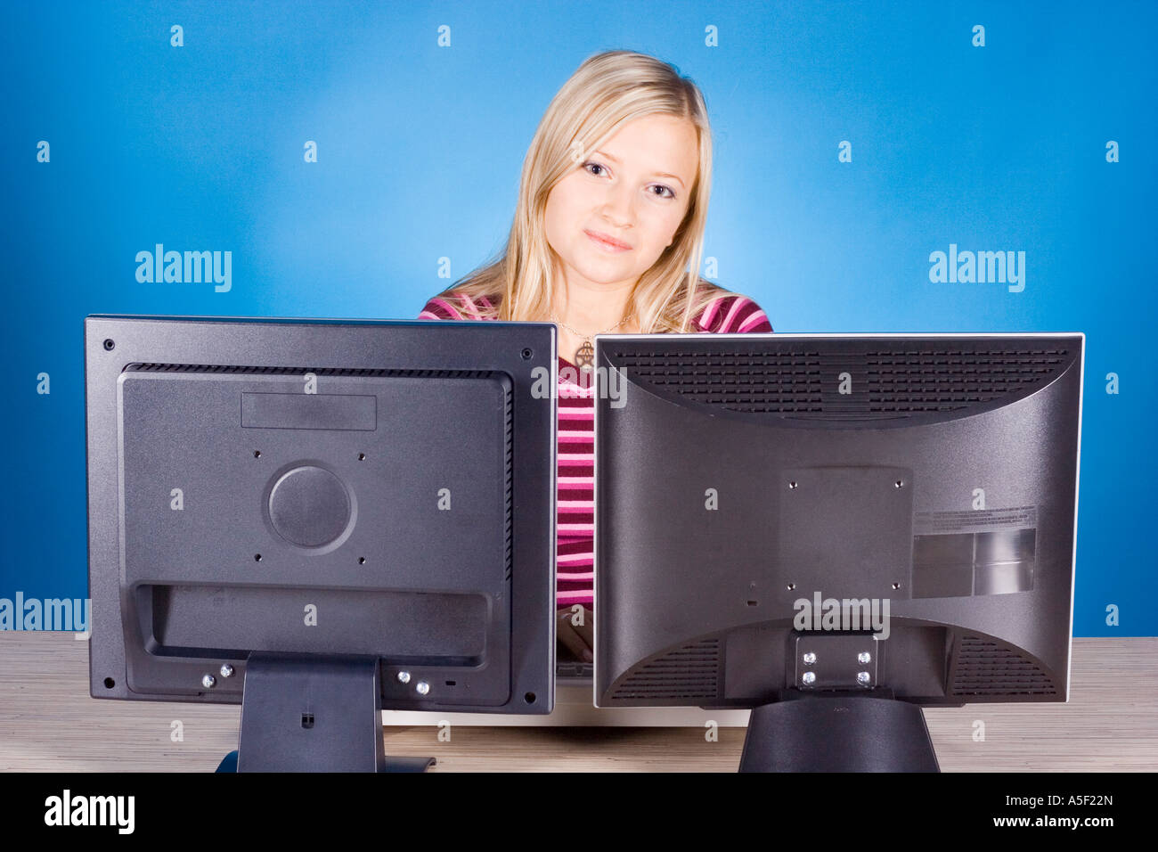 young blonde woman at the two computer s screens blue background Stock ...