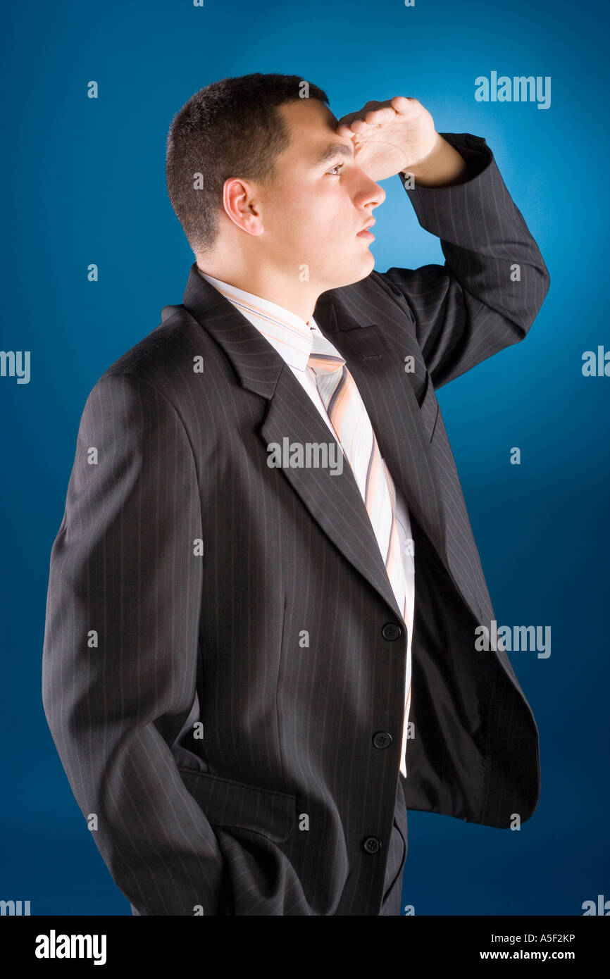 young businessman watching hand at his forehead blue background Stock ...