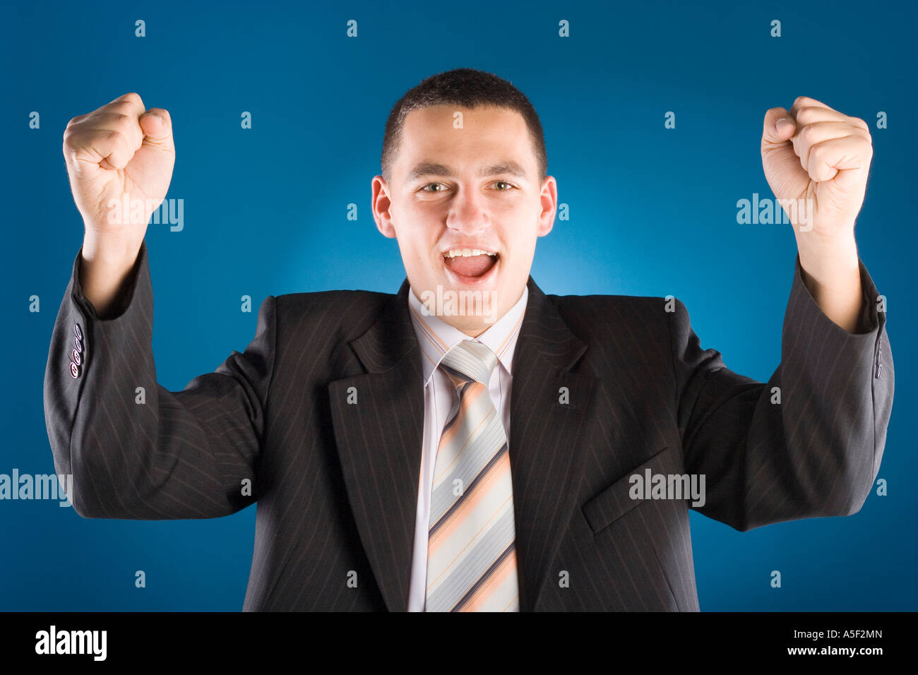 successful businessman with both hands up blue background Stock Photo ...