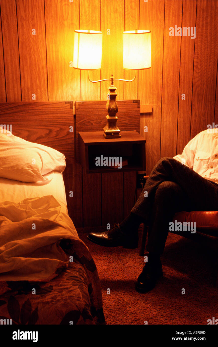 Evening Motel Room Scene Including Bed And Legs And Lightstand Stock