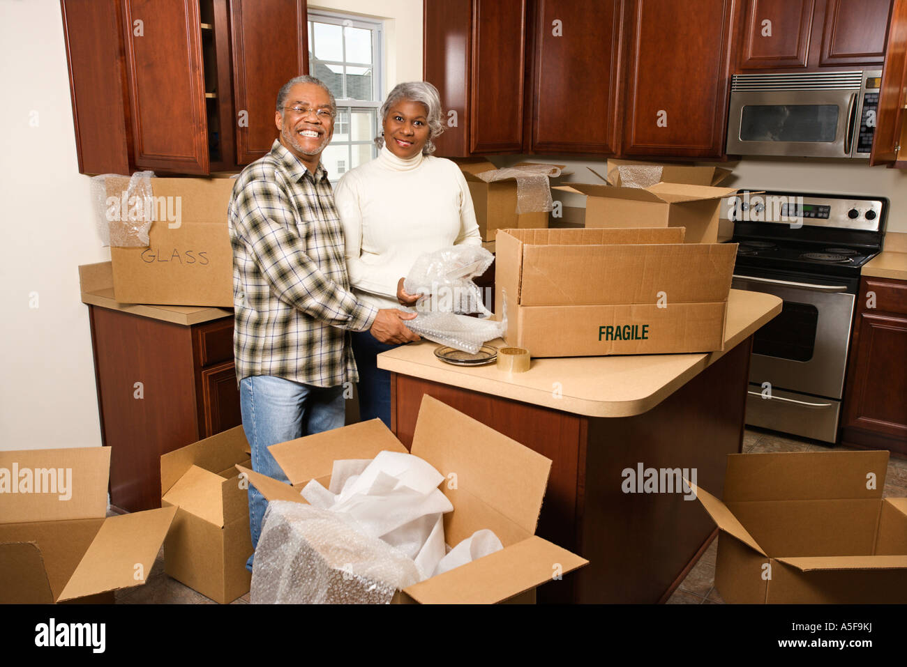 Portrait of middle aged African American couple packing moving boxes in ...