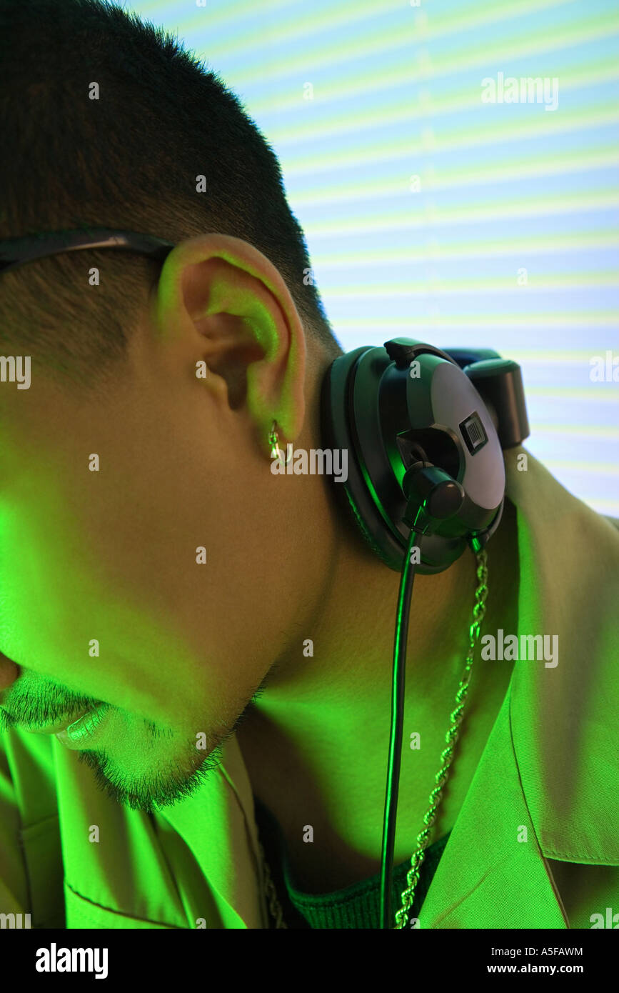Close up of Asian young adult male DJ s ear and profile with headphones ...