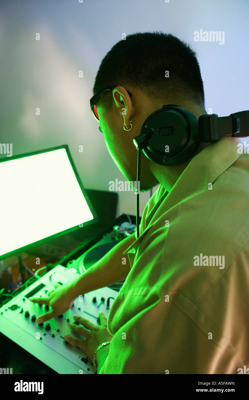 Rear view of Asian young adult male DJ mixing music on equipment Stock ...