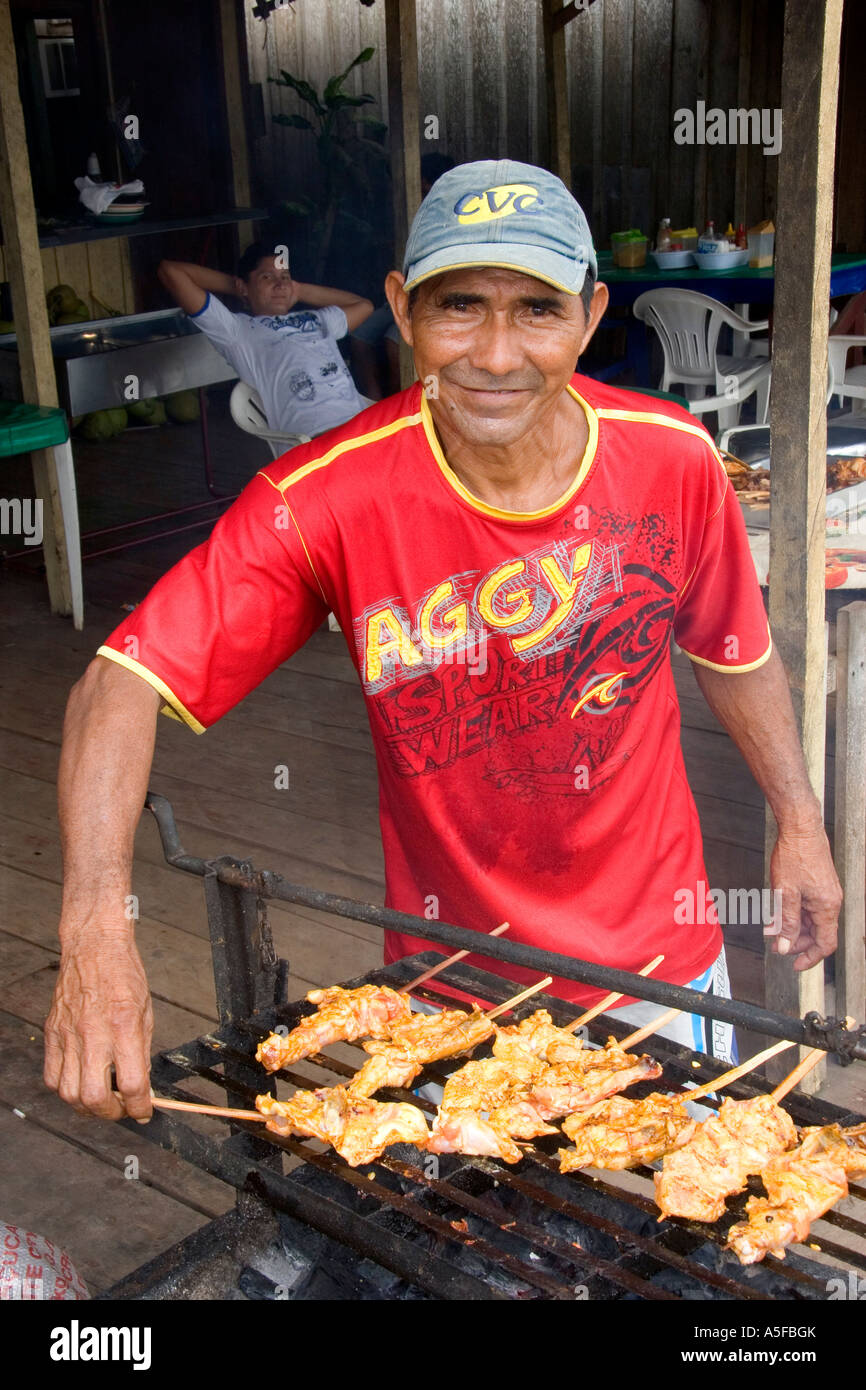 Brazilian man cooking chicken on a grill at a village in the Amazon ...