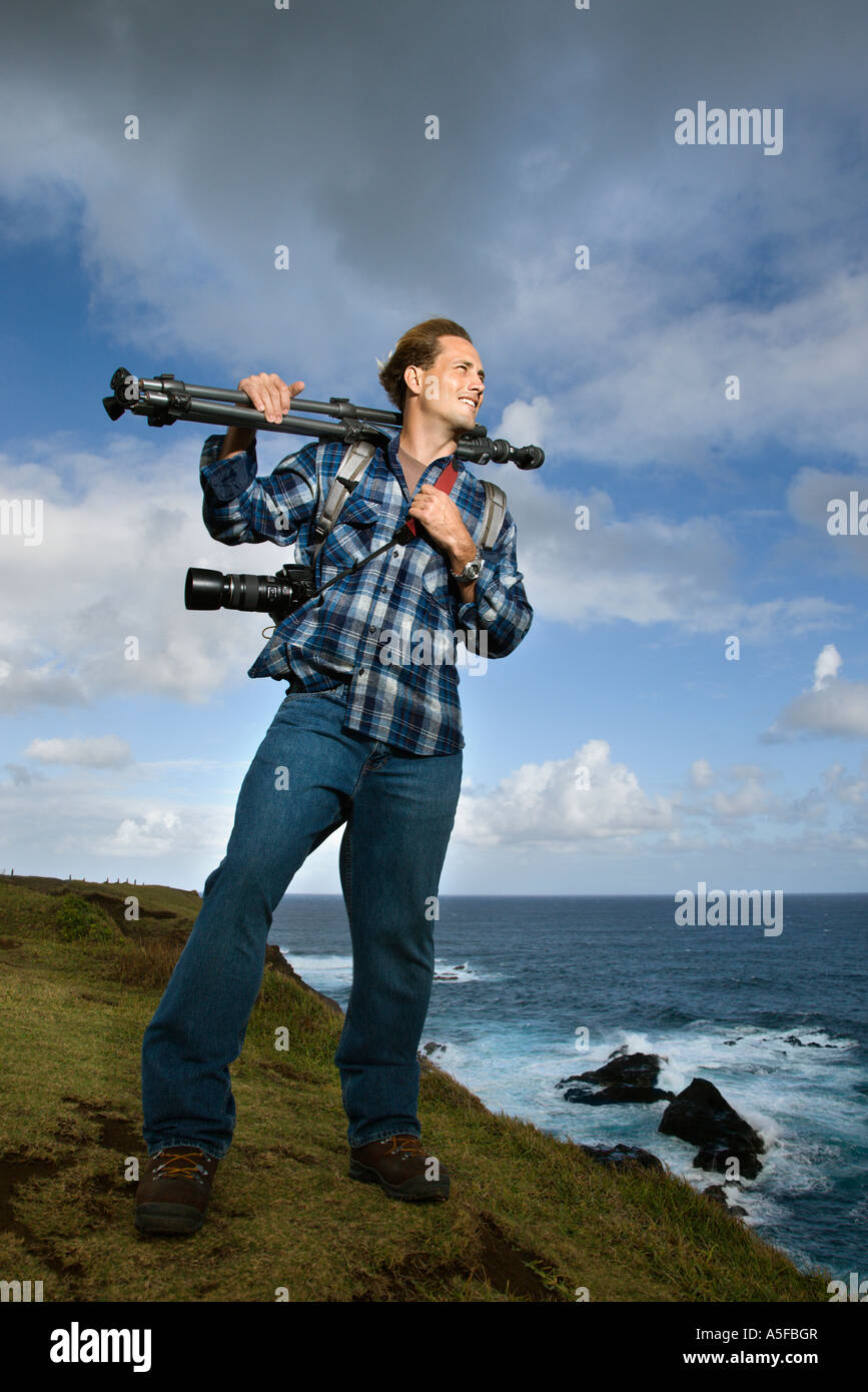 Caucasian mid adult man standing with camera and tripod over his ...