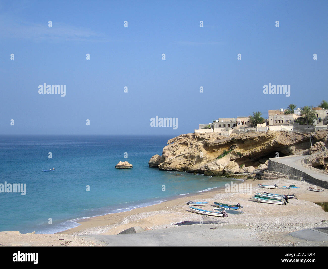Beautiful cove and a small Omani town with motorboats on the beach ...