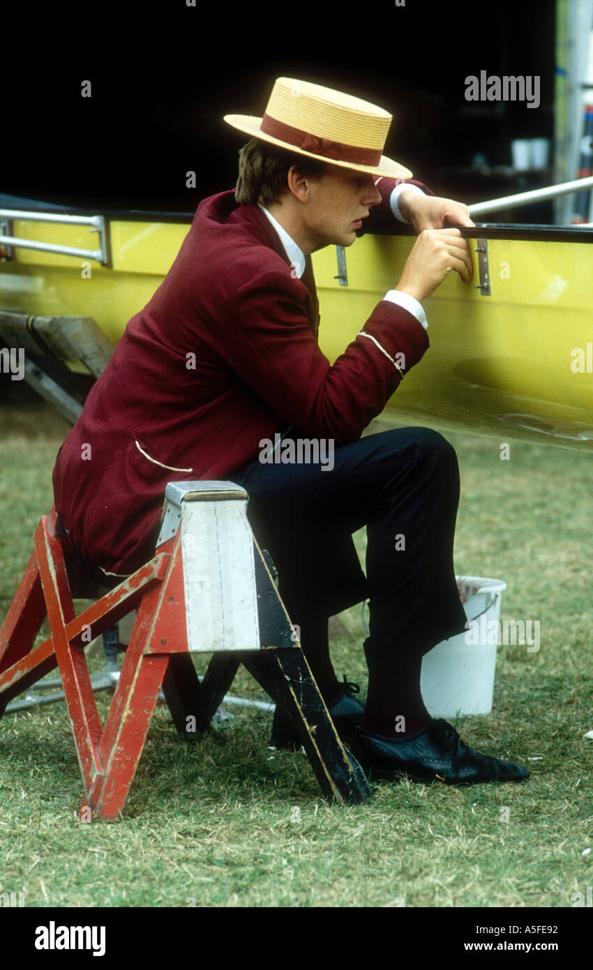A young man in a boater hat fixes a racing skiff at Henley Royal ...