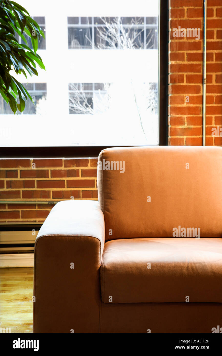 Cushy chair in loft apartment with houseplant in front of window Stock ...