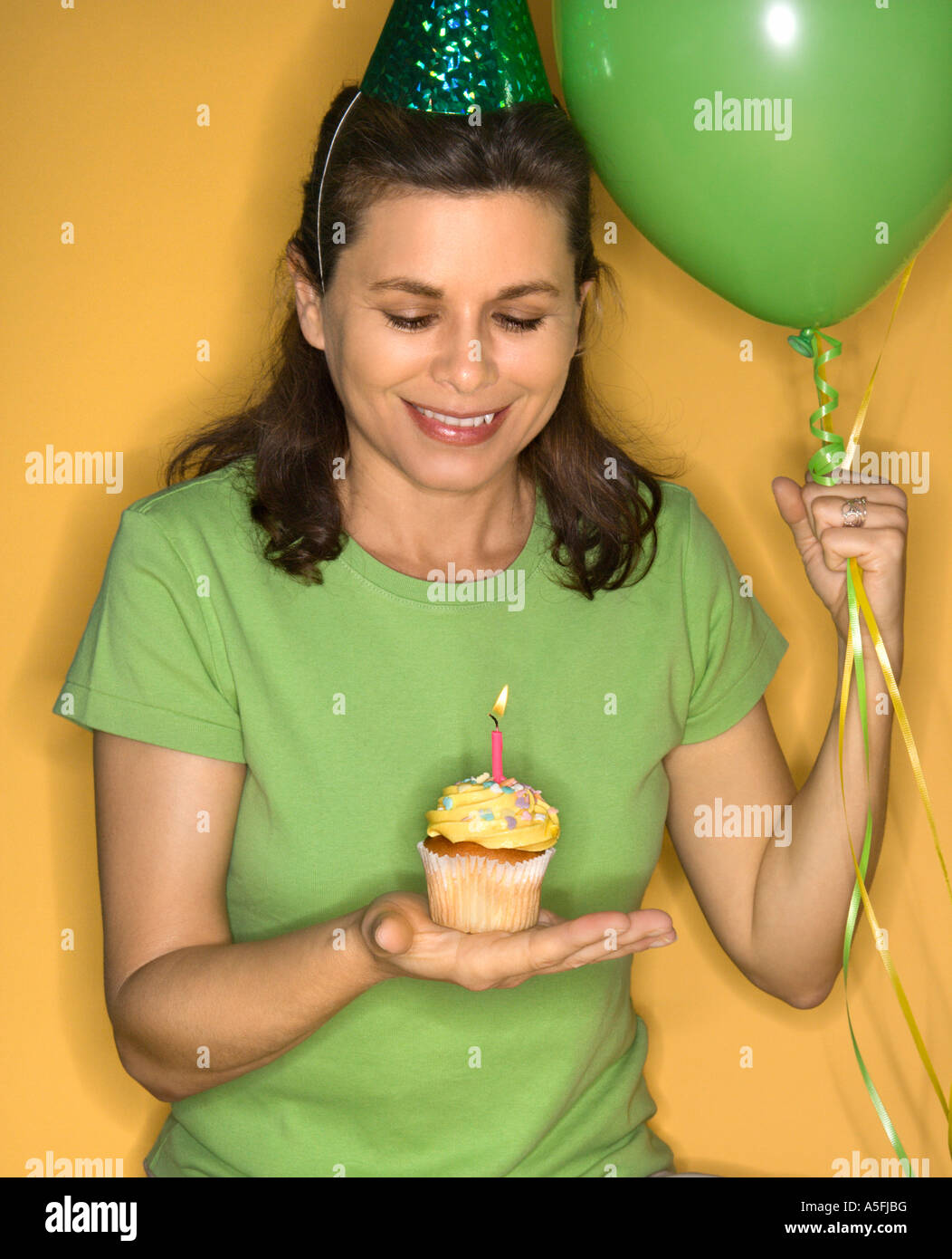 Caucasian prime adult female holding cupcake with lit candle wearing ...