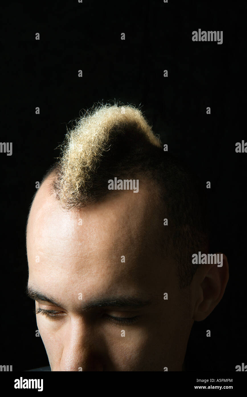 Portrait of Caucasian man in suit with mohawk against black background ...