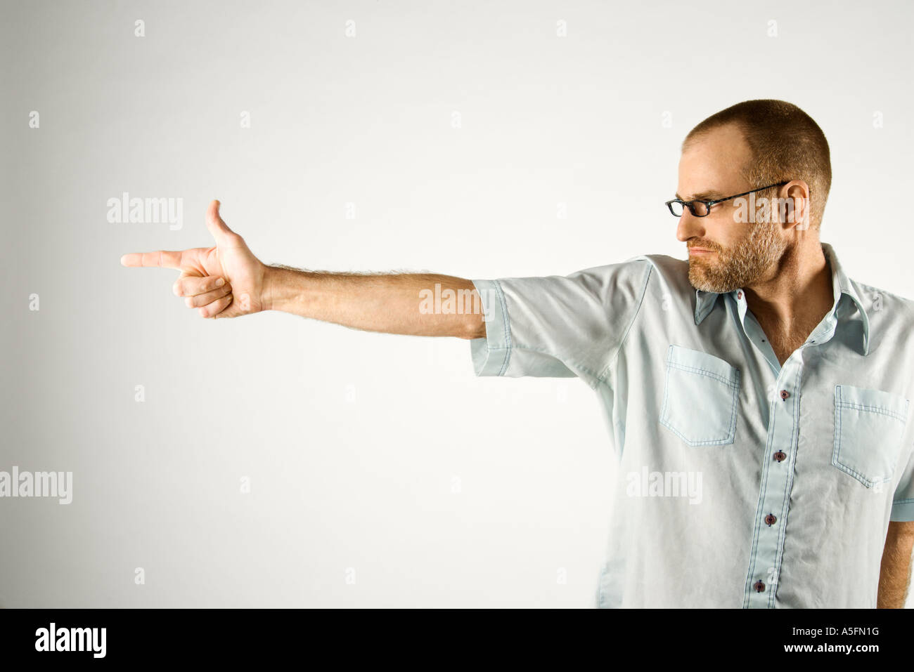 Portrait of Caucasian man holding hand out like a gun standing against ...