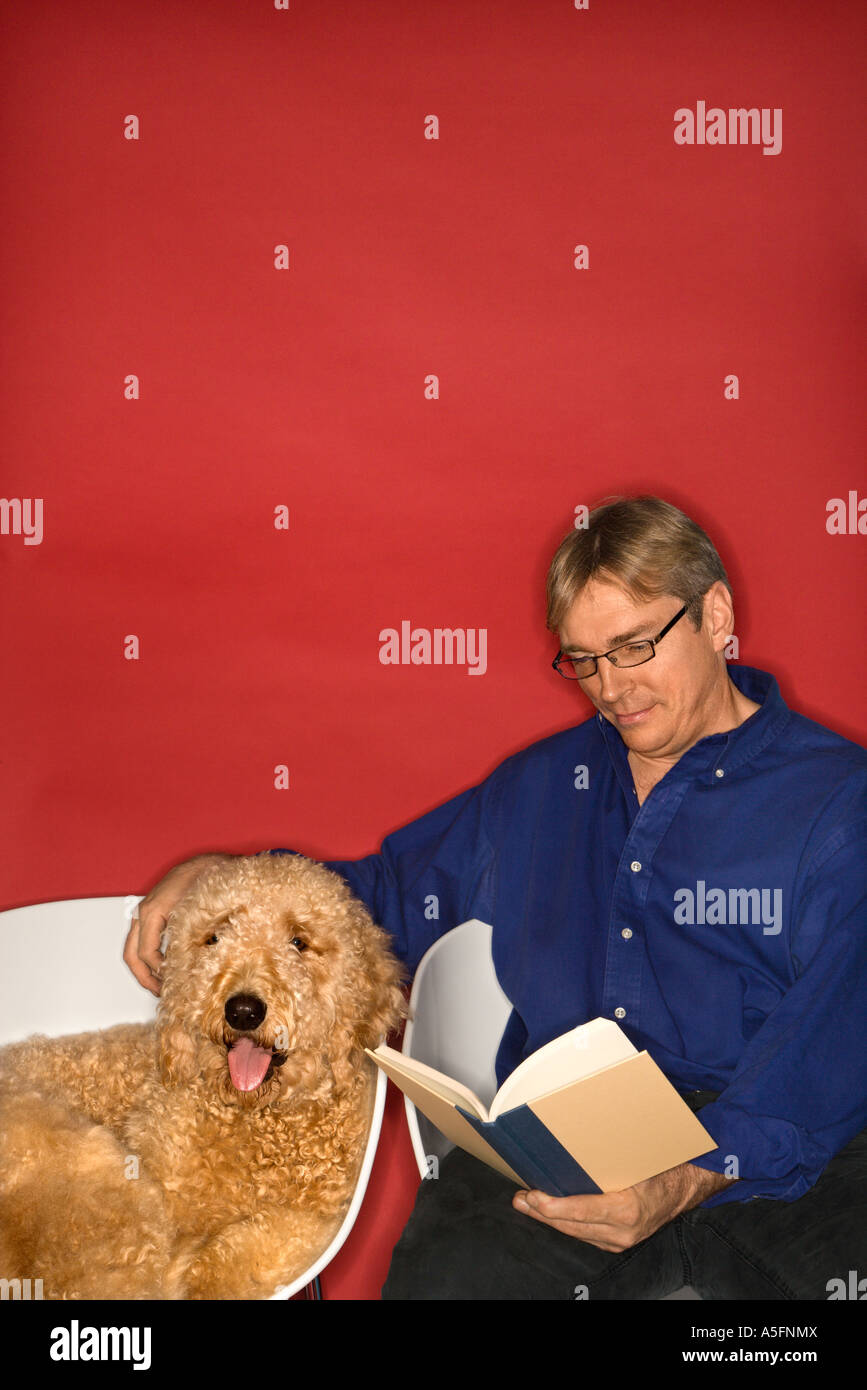 Middle aged Caucasian man with Goldendoodle dog reading book Stock ...