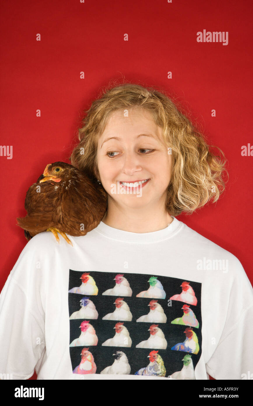 Caucasian mid adult woman looking at chicken on shoulder Stock Photo ...