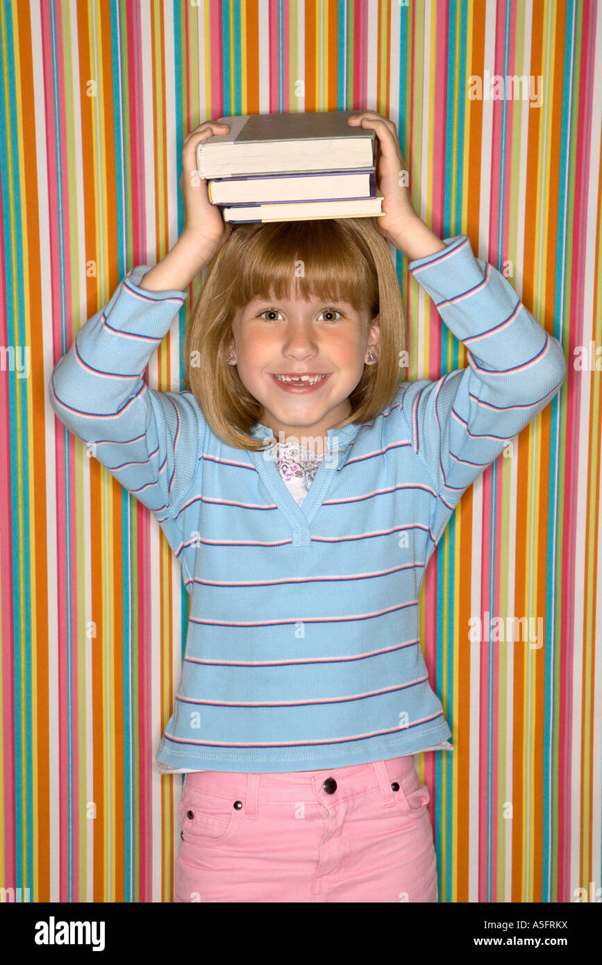 Caucasian female child balancing books on head Stock Photo - Alamy
