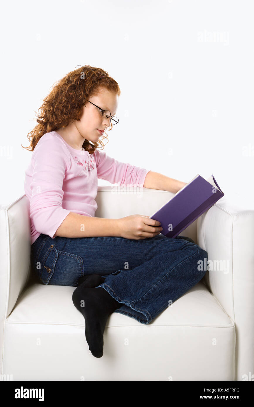 Caucasian female child sitting reading book Stock Photo - Alamy