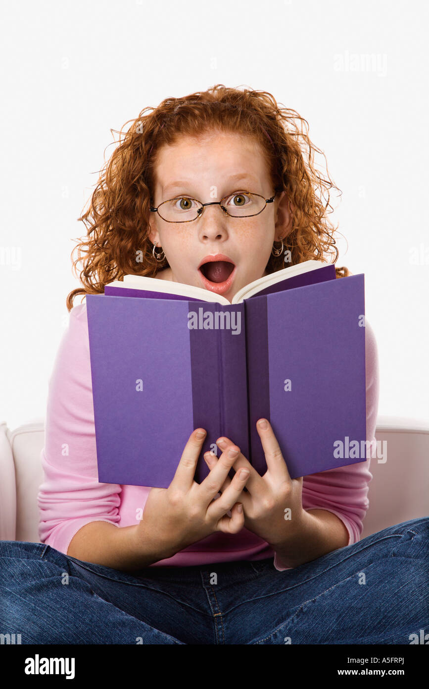 Caucasian female child sitting reading book looking surprised Stock ...