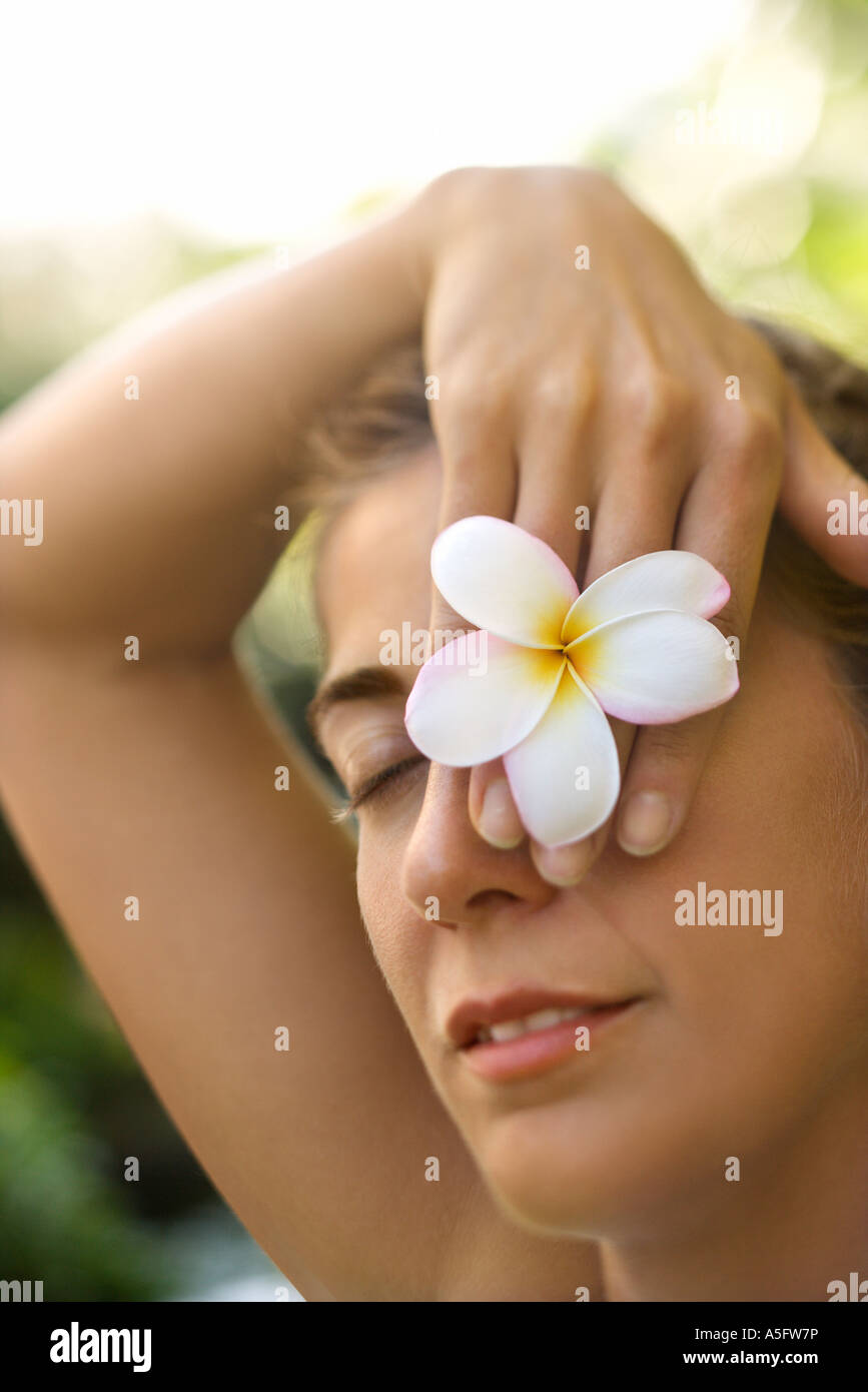 Caucasian mid adult woman holding plumeria flower over eye Stock Photo ...
