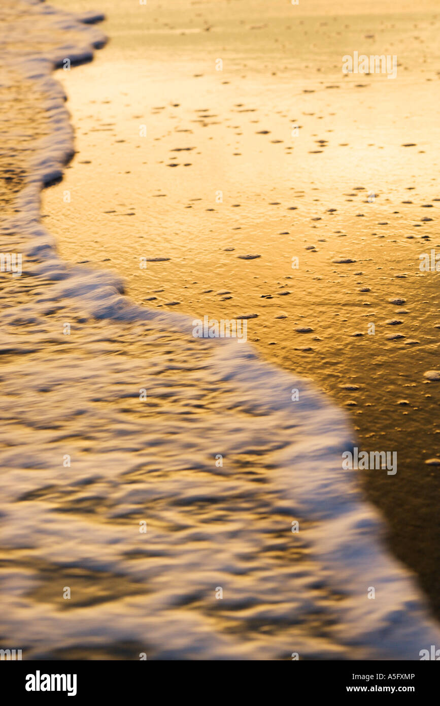 Waves lapping at beach at sunset Stock Photo - Alamy