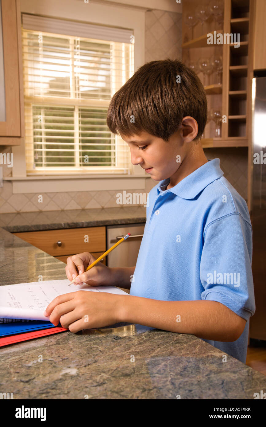 Caucasian pre teen boy doing homework at kitchen counter Stock Photo ...