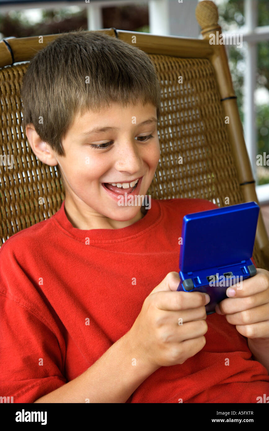 Caucasian pre teen boy playing handheld video game and smiling Stock ...