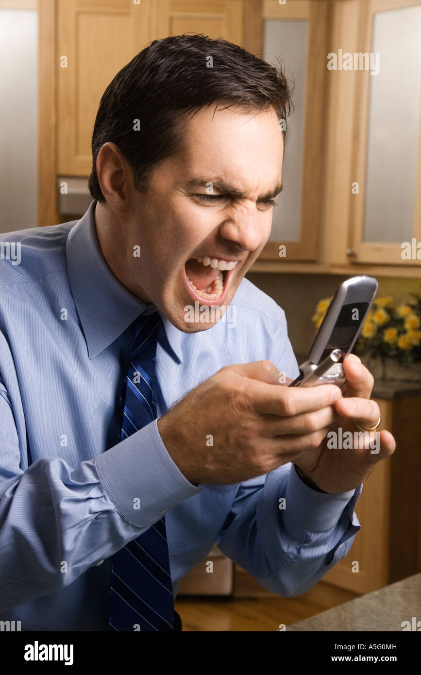 Mid adult Caucasian male screaming at cell phone while standing in ...