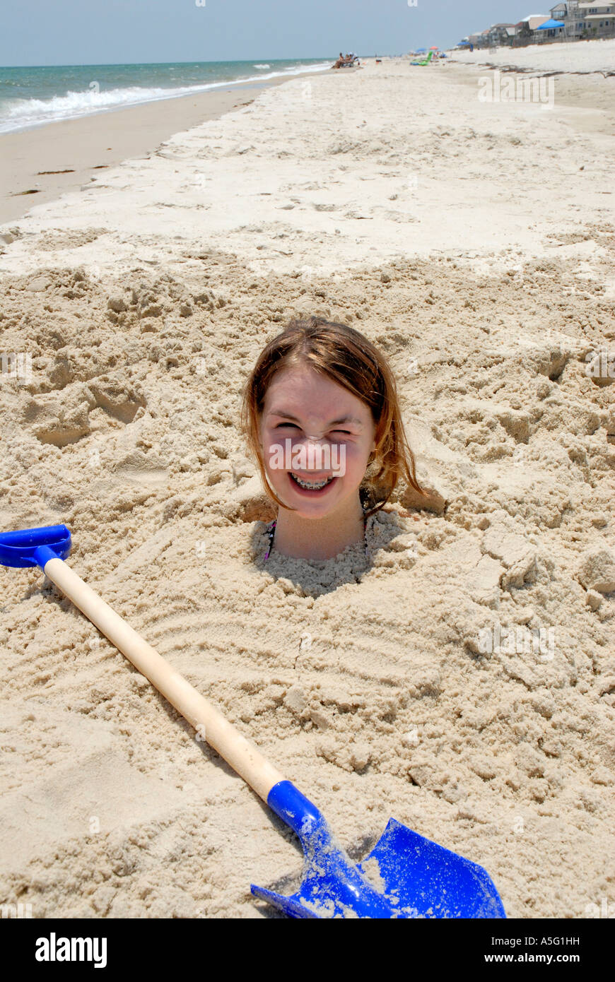 Girl buried in the sand Stock Photo - Alamy