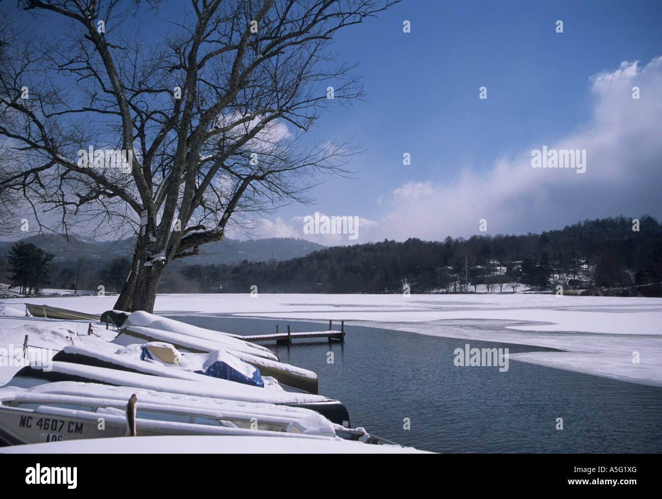 Partially frozen lake with snow-covered boats on shore Stock Photo - Alamy