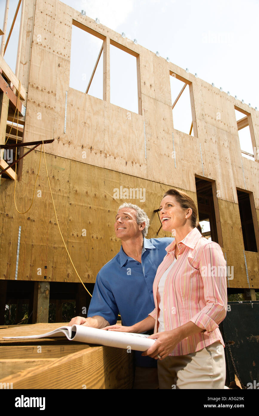 Caucasian mid adult male and female with blueprints observing building ...