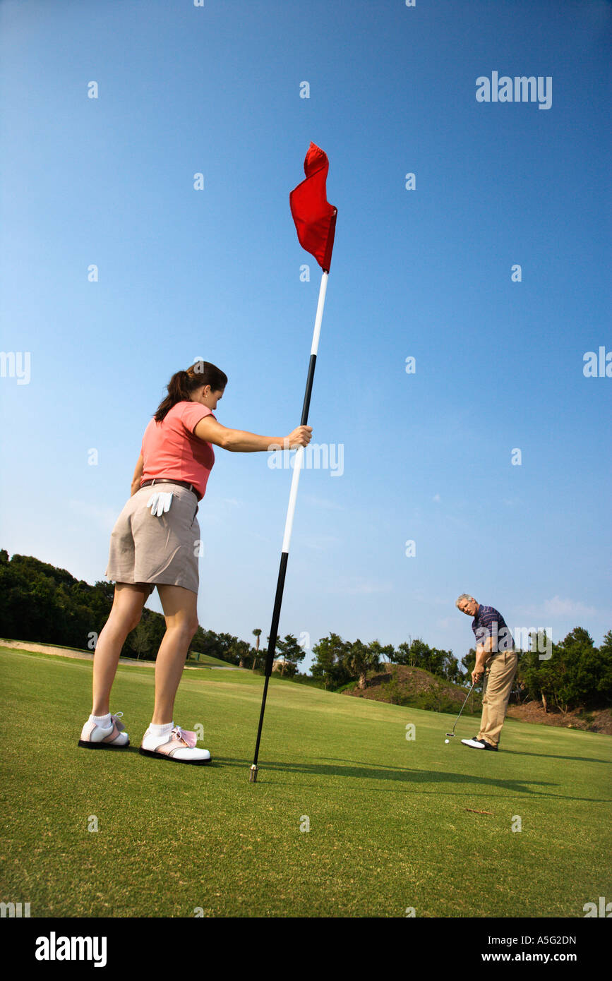 Caucasion mid adult man putting golfball while Caucasion mid adult ...