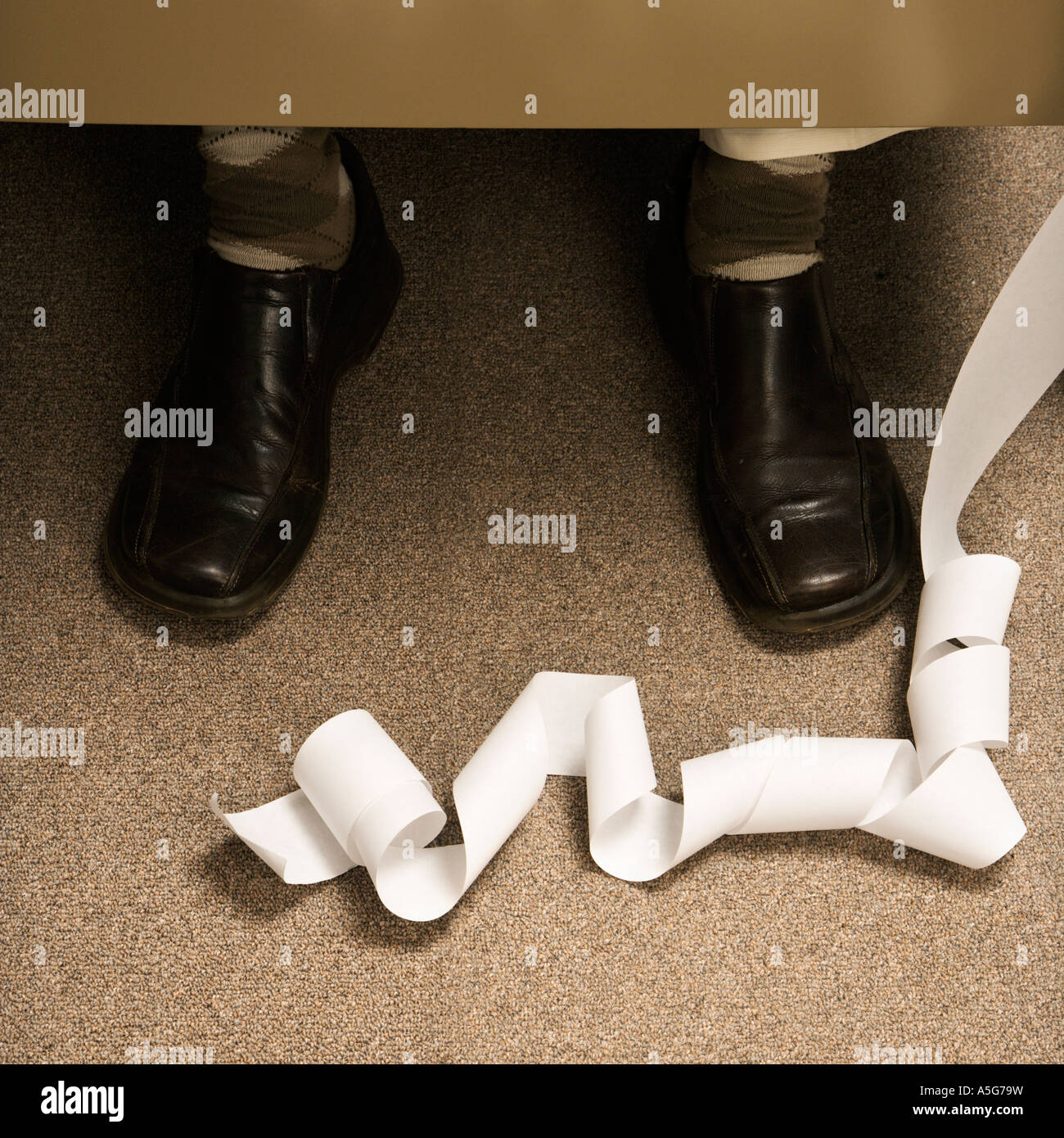 Long adding machine printout curled up at feet of retro businessman ...