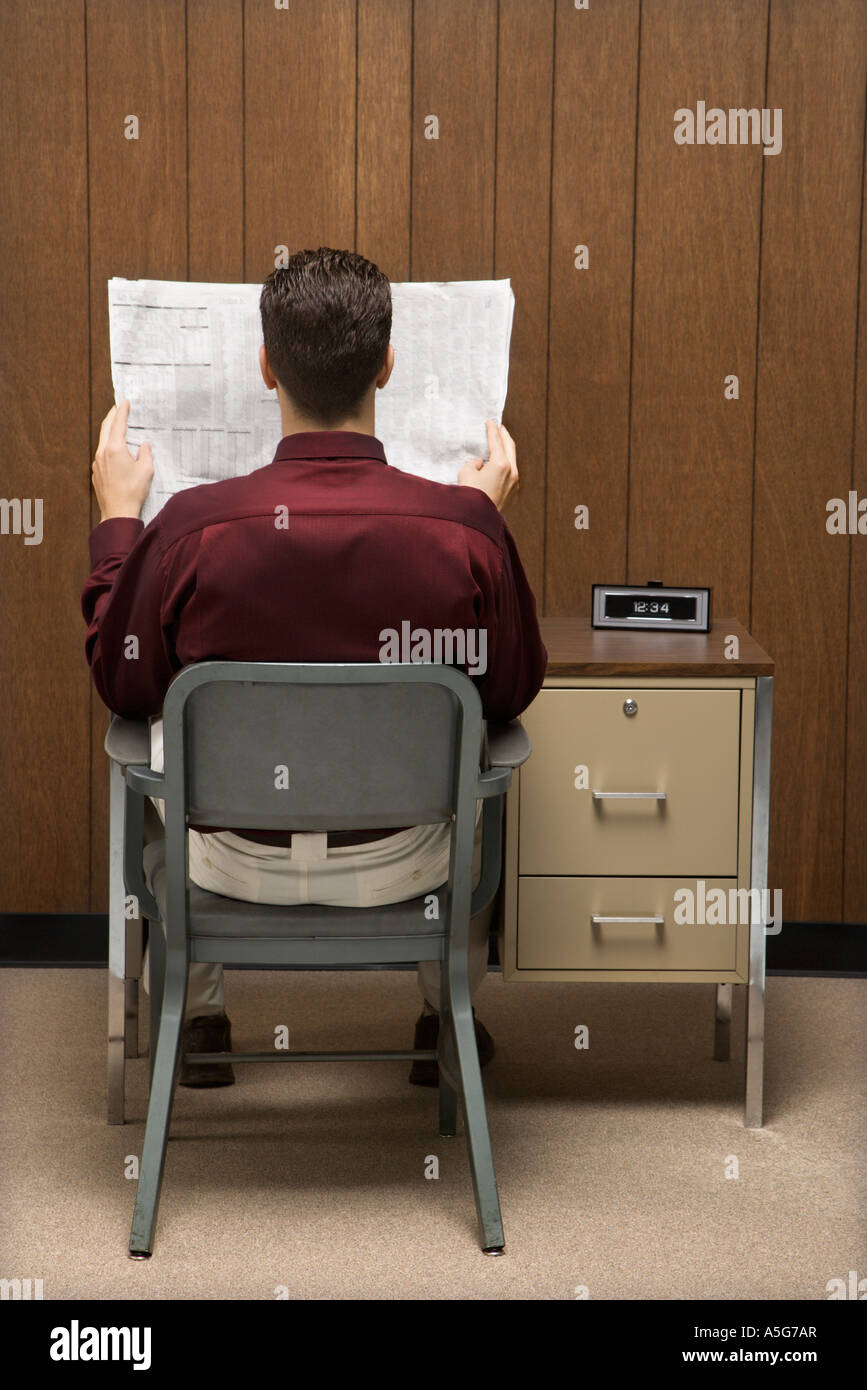 Back view of retro businessman sitting at desk reading paper Stock ...