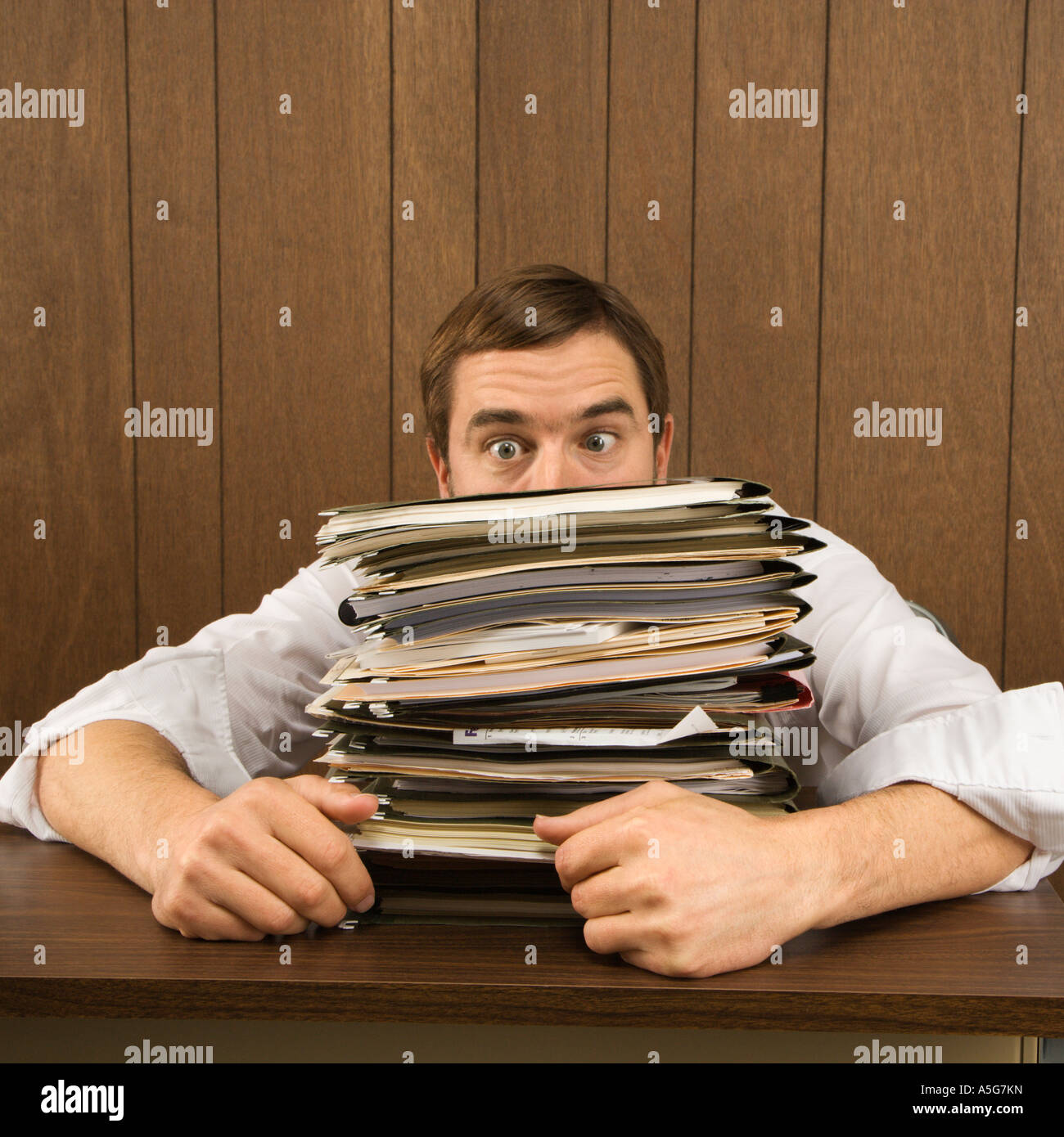 Mid adult Caucasian male peeking over big stack of paperwork Stock ...