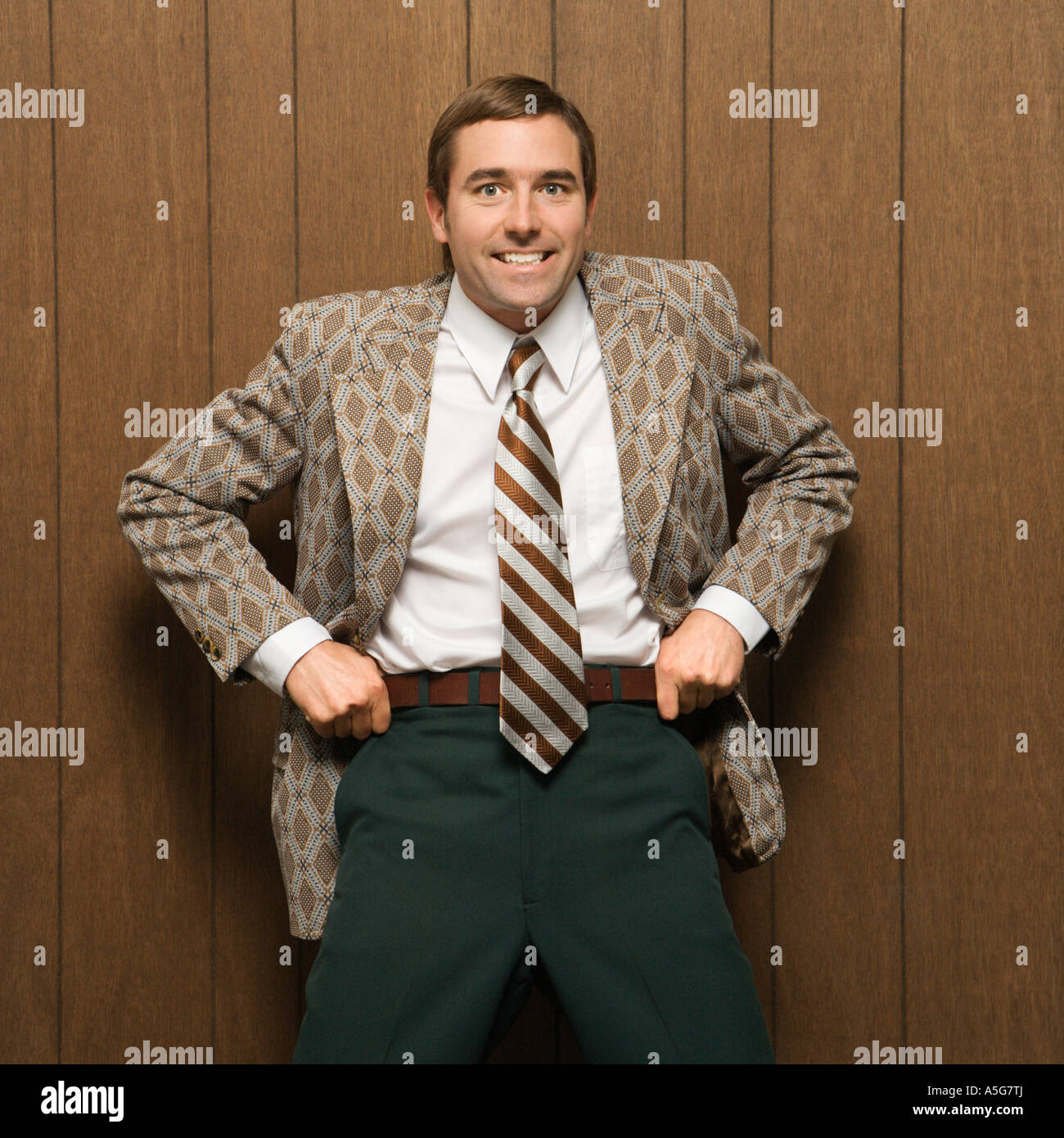 Mid adult smiling Caucasian male in retro suit pulling up on pants ...