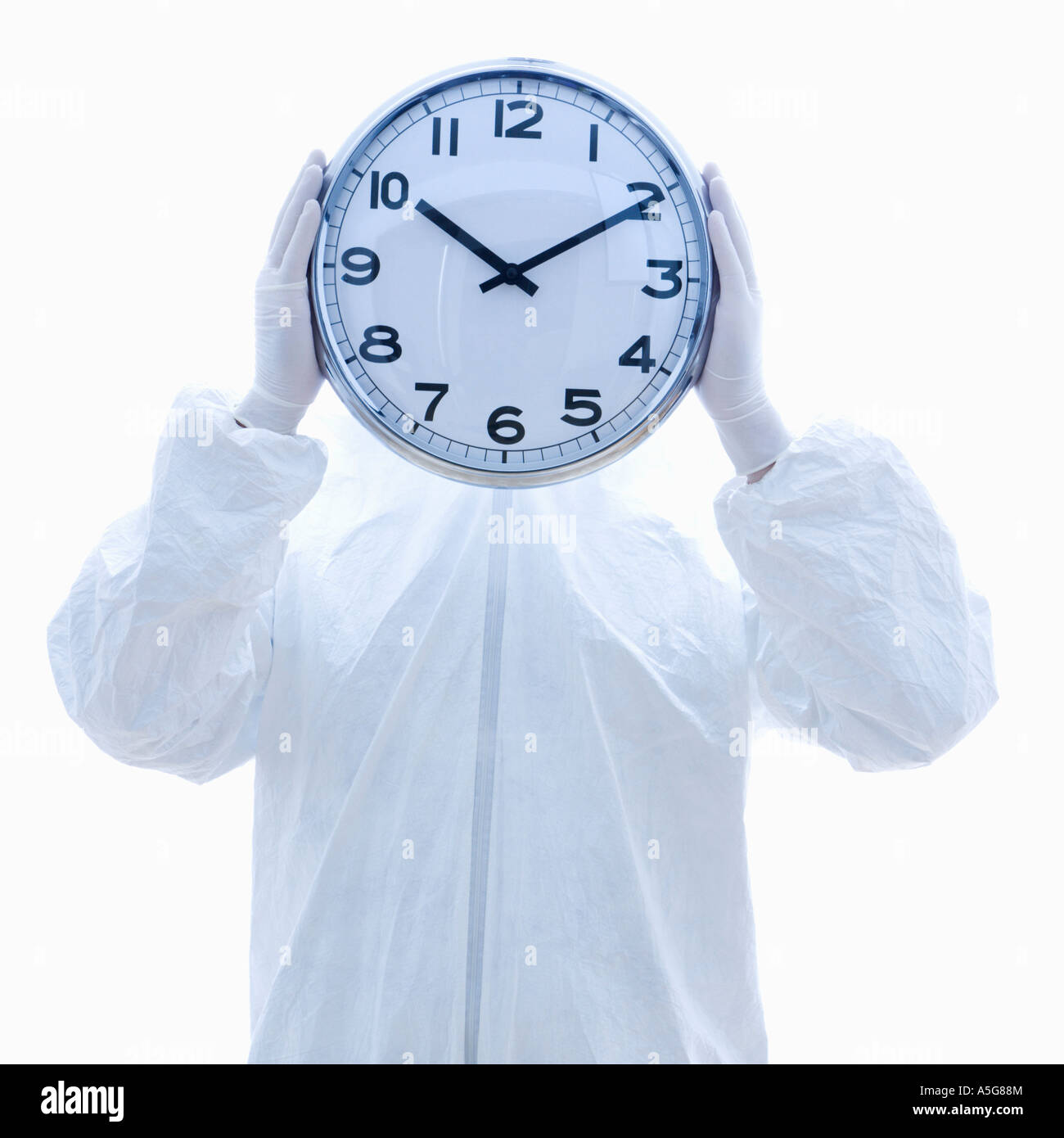 Man in biohazard suit holding clock in front of face standing against ...